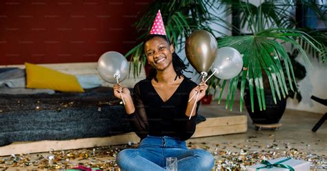 생일 모자를 쓰고 풍선을 들고 선물 상자 선물과 색종이와 함께 바닥에 앉아 있는 재미있는 아프리카계 미국인 소녀 축하·파티 컨셉 사진 Unsplash의 우크라이나 이미지