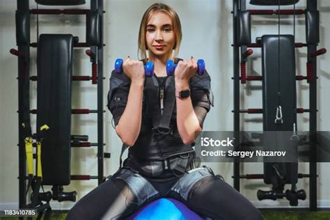 센서와 벨트를 착용한 소녀 체육관에서 Ems 피트니스를 연습하는 벨크로로 고정 아령으로 근육을 구축 운동 공에 앉아 강사에 대한 스톡 사진 및 기타 이미지 Istock