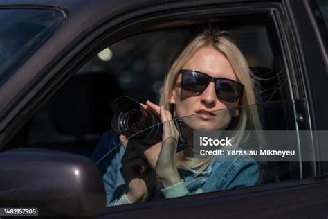 카메라가 달린 선글라스를 쓴 여자는 차에 앉아 전문 카메라 사립 탐정 또는 파파라치 스파이와 함께 사진을 찍는다 기자는 감각을 찾고 유명인을 따릅니다 Theatrical