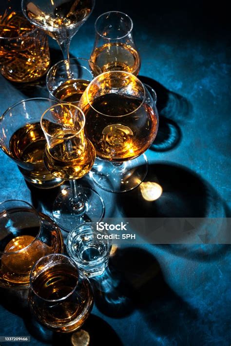 코냑 스카치 위스키 등 강력한 알코올 음료 하드 주류 증류주 및 증류소 이셋을 안경에 넣고 있습니다 파란색 배경 상단 보기 데킬라 독한 술에 대한 스톡 사진 및 기타 이미지