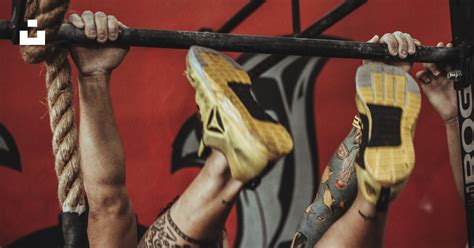 노란색과 검은색 리복 로우탑 운동화를 신고 풀업 바에 매달려 있는 사람 사진 Unsplash의 무료 감바루 크로스핏 이미지