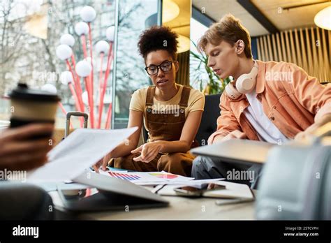 Two Colleagues Engage In A Focused Discussion Analyzing Charts And Documents At A Hotel Stock