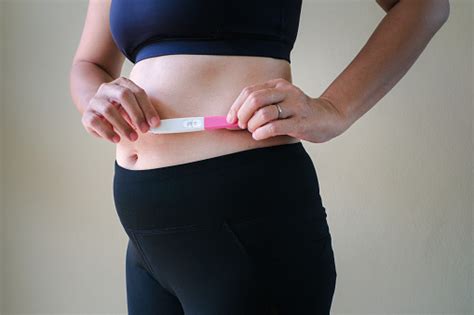 두 줄무늬와 임신 테스트를 보여주는 손을 닫습니다 긍정적 인 결과 임신 테스트 스트립에 초점을 맞췄습니다 6 주 빈티지 톤