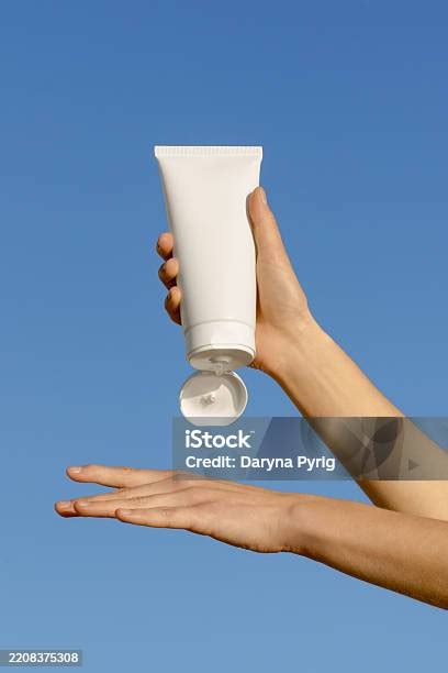 파란색 고립 된 하늘 배경에 피부에 흰색 모형 튜브에서 크림을 짜내는 여성 손의 수직 이미지 미용 스킨 케어 Spf로 보호의 개념 25 29세에 대한 스톡 사진 및 기타