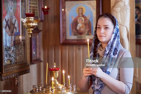 빨간 머리카락과 머리에 스카프를 씌운 러시아 정교회의 여성이 촛불을 켜고 아이콘 앞에서기도합니다 35 39세에 대한 스톡 사진 및 기타 이미지 Istock