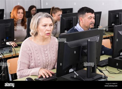 Computer Lessons For Adults Mature Woman Learning To Use Computer In Classroom With Group Stock