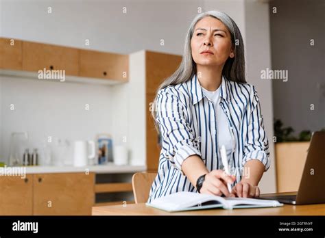 Serious White Haired Mature Woman Writing Down Notes Working With