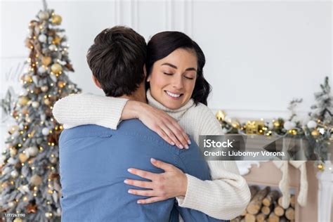 크리스마스에 함께 새해를 축하하는 가족 커플 거실의 크리스마스 트리 근처에 서서 즐겁게 미소 짓고 포옹하는 남녀 사랑에 빠진 남자와 여자 2명에 대한 스톡 사진 및 기타