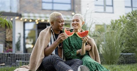 정원에서 수박을 먹는 다인종 커플 관계의 개념과 함께 시간을 즐기는 것 현대적인 라이프 스타일 유럽인 여자친구를 껴안고 있는 흑인 남성 격자 무늬로 덮인 사람들 사진