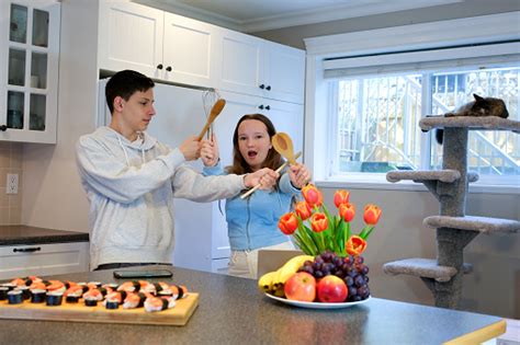 부엌에서 춤을 추는 행복한 십대들 웃는 소녀는 십대 소년에게 씻으라고 가르치고 요리하거나 먹기 전에 춤을 추고 집에서 함께 가족 생활을 즐긴다 2명에 대한 스톡 사진 및