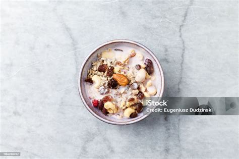 요구르트 견과류 건포도 크랜베리 치아 씨앗을 곁들인 그래놀라 그릇 맛있고 건강한 식사를 위한 컨셉 돌 배경입니다 맨 위 보기