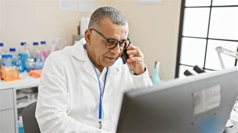Concentrated Hispanic Man Wearing Glasses And Lab Coat Analyzing Data