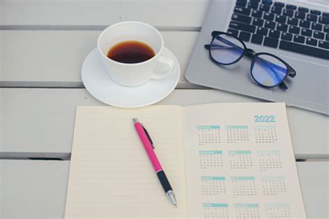 플래너는 캘린더 책에서 회의 의제를 작성하고 집에서 온라인으로 작업합니다 주최자가 사무실 책상에서 시간표 일일 약속 및 관리 작업을 계획하기위한 일기 플래너 책 및 2022