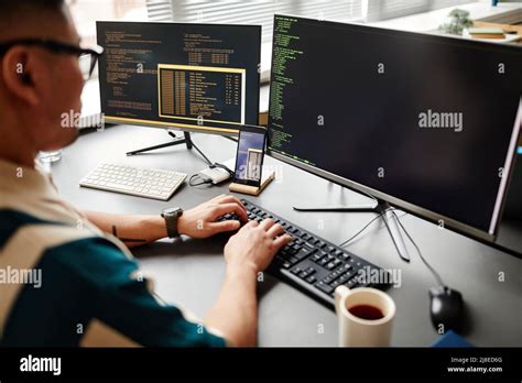 Closeup Of IT Developer Typing On Keyboard With Programming Code On Computer Screen While