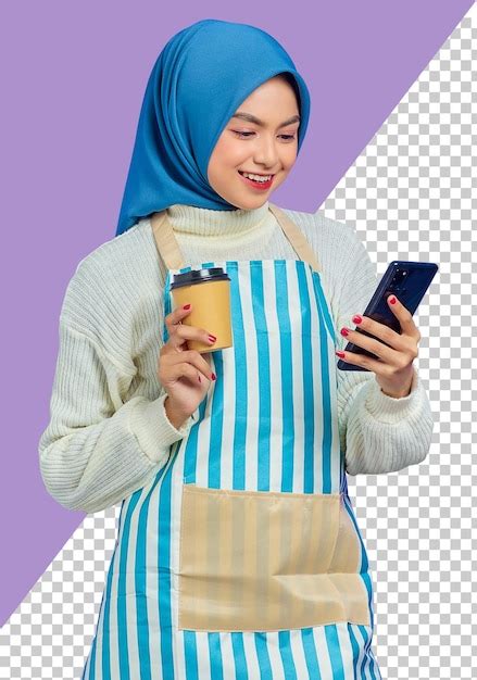 히잡을 쓰고 앞치마를 두른 20대 아시아계 이슬람 여성이 휴대전화와 종이 커피 컵을 들고 보라색 배경에서 격리된 주부 이슬람