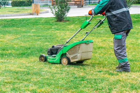 Premium Photo The Gardener Cutting Grass By Lawn Mower