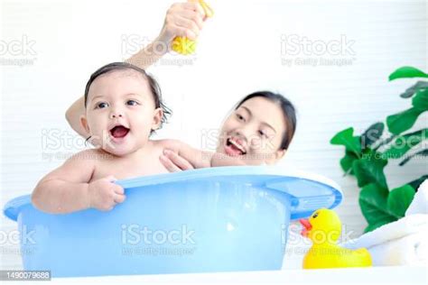 행복한 유아 아기는 욕실에서 거품 목욕을 하고 욕조에서 아이를 목욕시키고 엄마는 목욕에서 어린 유아 소녀 딸 아이를 씻고