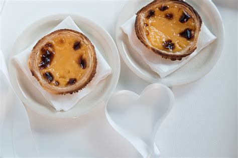 파스텔 데 나타 포르투갈 요리의 전통적인 단맛 작은 바삭 바삭한 퍼프 패스트리 파이와 계란으로 만든 크림 종종 커피를 맛보고 동반합니다 흰색 배경에 두 개의 파스텔 데 나