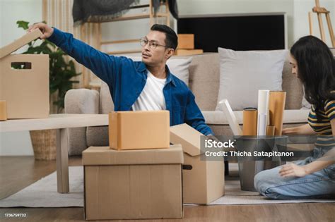 젊은 부부는 집에서 골판지 상자 주위에 바닥에 앉아 휴식을 취하고 새 집으로 이사하는 행복한 미소를 짓고 있다 25 29세에 대한 스톡 사진 및 기타 이미지 Istock