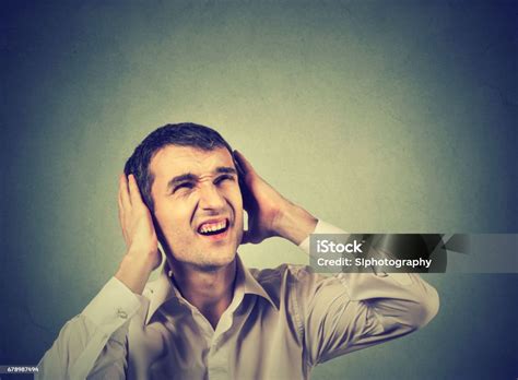 화가 불행 스트레스 젊은이 그의 귀를 덮고 찾고 중지 하 고 시끄러운 소음 나에 게 두통을 주고 가리기에 대한 스톡 사진 및