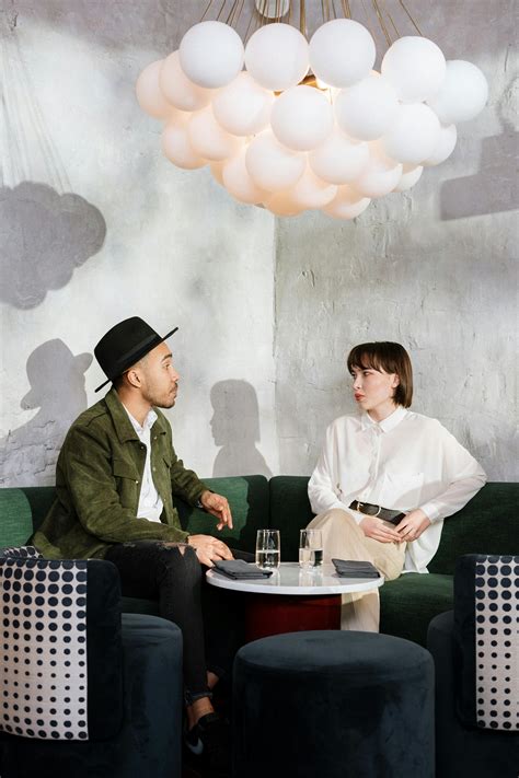 가벼운 대화 교수형 램프 구름 날짜 남성 패션 녹색 소파 대비 조명 대화 따뜻한 조명 라운드 테이블 레스토랑 막대기 말하는 모자 물 유리 미니멀