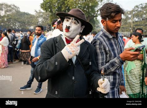 an entertainer dressed to resemble charlie chaplin reacts to camera as as people enjoy new year
