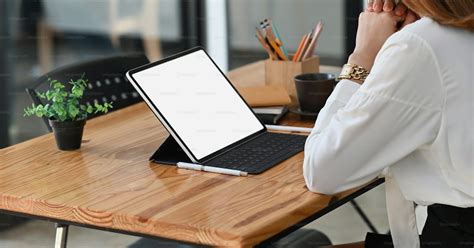 비서로 일하는 젊은 아름다운 여성의 사진은 질서 정연한 사무실을 배경으로 현대적인 나무 테이블에서 키보드 케이스가 있는 흰색 빈