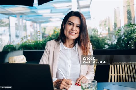 카페 테라스에 앉아 있는 거리 일자리를 계획하고 프리랜서 제작 출판물에서 원격으로 일하는 카메라를 바라보는 여성 작가의 미소 짓는 부유한 사업가의 초상화 35 39세에 대한