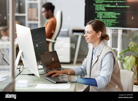 Smiling Woman With Bionic Arm Coding On Computer When Working On Big Project At Research Center