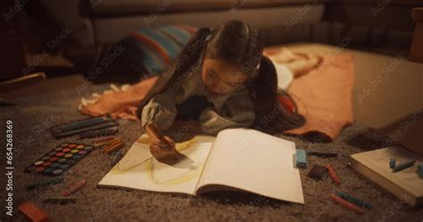 거실 바닥에 엎드려 열심히 그림을 색칠하는 소녀의 영상 시네마틱 줌인 돌리 Vídeo De Stock Adobe Stock