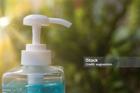 블루 알코올 젤 병의 펌프를 닫아 녹색 자연 배경과 태양 광선을 흐리게 합니다 펌프 병에 손 소독제 젤 텍스트 또는 디자인을