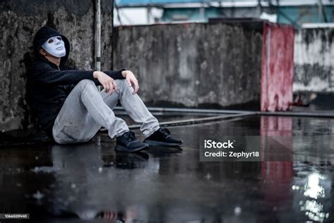 미스 테리 까마귀 남자가 흰색 마스크 버려진된 건물의 옥상에 하늘 보면 비에 앉아 있다 양극성 장애 또는 주요 우울증 장애입니다 우울증 개념 가린 얼굴에 대한 스톡 사진 및
