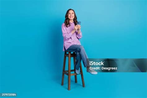 매력적인 긍정적 인 여자 착용 바이올렛 셔츠 앉아있는 의자 통신 현대 가제트 빈 공간 외딴 파란색 배경의 전체 길이 사진 65 69세에 대한 스톡 사진 및 기타 이미지