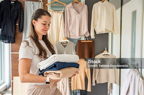 한 청녀가 손에 옷 뭉치를 들고 재판매 기부 또는 재활용을 위해 옷을 분류하고 있다 지속 가능한 패션과 중고 사용은 폐기물을 줄이고 의식 있는 소비를 촉진하는 데 도움이
