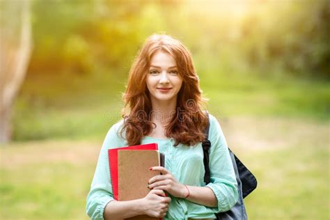 Attractive Redhead Babe Girl With Backpack And Workbooks Posing At Campus Yard Stock Photo