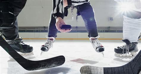 아이스링크에 퍽을 들고 있는 하키 심판은 훈련 중 가장 먼저 쏠 순간을 기다리는 막대기를 들고 두 선수 사이에 퍽을 들고 있다