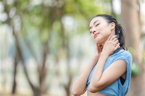 도시의 공원에서 조깅 운동을 한 후 몸과 목을 스트레칭하는 아시아 여성 운동복을 입은 매력적인 운동 선수 소녀는 아침 여름에 야외 라이프 스타일 스포츠 훈련 피트니스 달리기