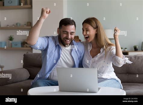 Cheerful Excited Millennial Husband And Wife Making Winner Yes Hands