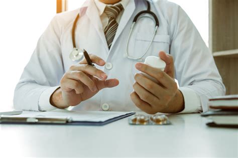 자신감 있는 의사 남자 알 약 병을 들고 하 고 수석 환자와 이야기 하 고 사무실 방에서 그의 약물을 검토 하는 동안 쓰기 개념에 대한 스톡 사진 및 기타 이미지 Istock