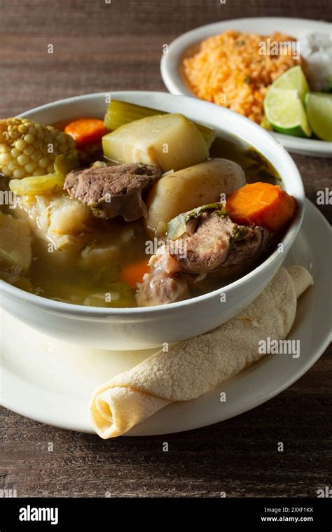 A View Of A Bowl Of Caldo De Res With A Side Of Rice And Toppings