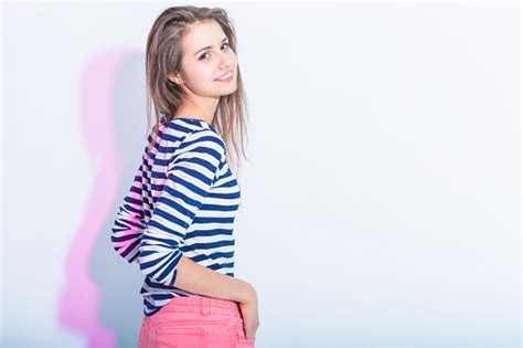 스트라이프 셔츠와 핑크 반바지에 웃고 코카서스 갈색 머리 소녀의 초상화 반은 흰색을 향해 뒤로 돌아섰다 수평 이미지 방향 20