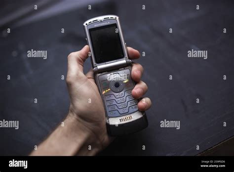 A Person Holding An Open Motorola Flip Phone Against A Dark Background Motorola Razr V3 Stock
