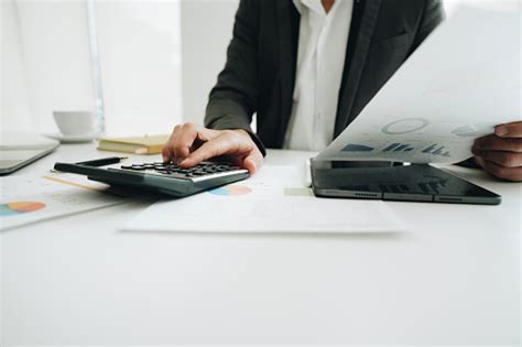 사업가 또는 회계사는 사무실에서 회계 문서를 사용하는 동안 비즈니스 데이터를 계산하기 위해 계산기와 랩톱 컴퓨터에서 작업합니다 개발에 대한 스톡 사진 및 기타 이미지