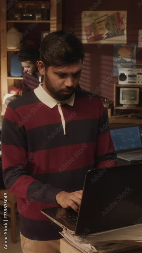 Vertical Medium Shot Of Young Biracial Male Programmer Wearing Striped Vintage Long Sleeved Polo