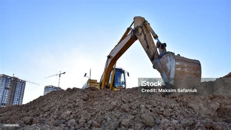 가장 큰 건설 현장에서 작업하는 굴삭기 토목 공사의 백호 외부 하수도 파이프를 놓는 로더를 추적했습니다 0명에 대한 스톡 사진