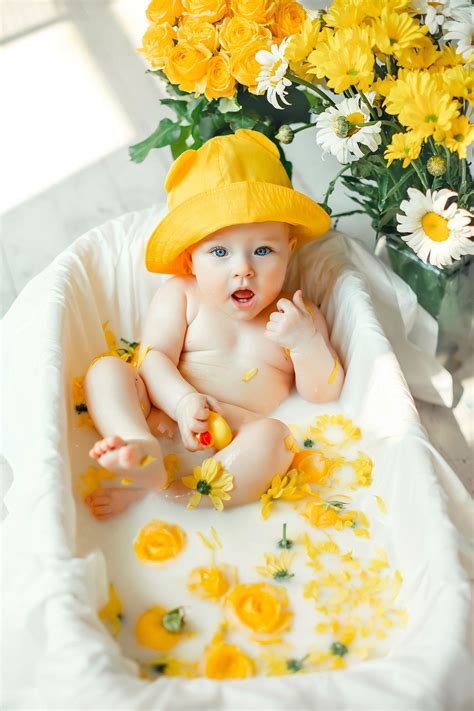 Девочка в желтой панамке купается в ванной с цветами Новорожденные