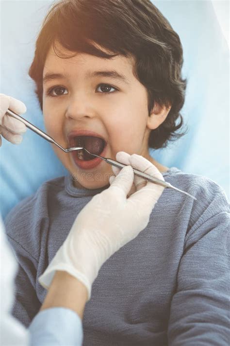 Cute Arab Boy Sitting At Dental Chair With Open Mouth During Oral