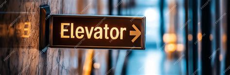 Elevator Sign Directing To Lift Illuminated In Modern Hallway Warm Glow