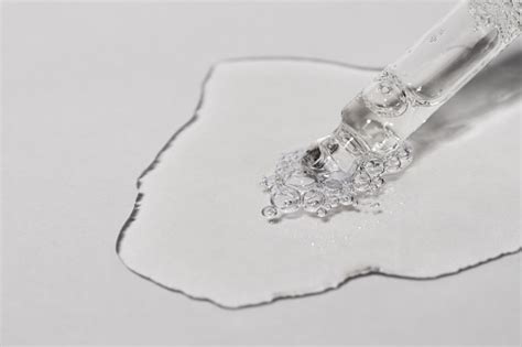 회색 배경에 피펫에서 거품이 쏟아지는 페이셜 세럼 또는 오일의 매크로 드롭 화장품 스킨 케어 제품 광고 레티놀 또는 히알루론산이