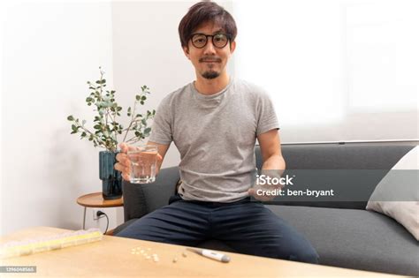 성인 아시아 남자는 보충 교재 또는 알약을 먹고 집에서 소파에 앉아 45 49세에 대한 스톡 사진 및 기타 이미지 45 49세 건강관리와 의술 남성 Istock